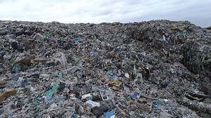 Aerial drone view of large garbage landfill, trash dump, waste from household dumping site, excavator machines are working.