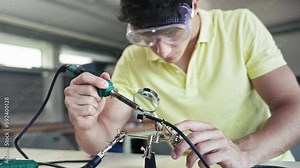 Teenager Student soldering electronics cable, learning engineering and technology