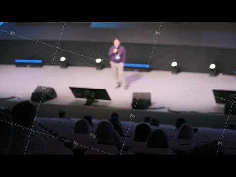 Speaker on stage delivering talk at conference with photographer