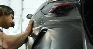 Close up of paint protection film installation on modern luxury car. PPF is polyurethane film that wrap car paint to protect paint surface from stone chips, bug splatter, and abrasion.