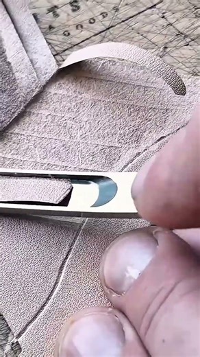 Shaving the top layer of light brown leather using a professional metal skiving tool