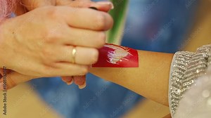 The process of applying a temporary tattoo of sequins to the arm. decoration and entertainment at the holiday.