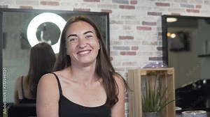 Funny fat beauty salon visitor with black eyebrows painted. Woman with painted eyebrows laughs at the beautician's chair