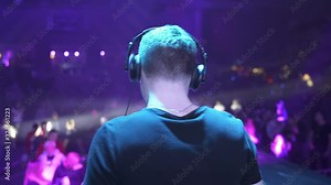 DJ stands behind the mixer, DJ controller, mixes music, twists the levers, shooting hands close-up, nightclub, artificial lighting, light music purple, yellow, blue, Night club party
