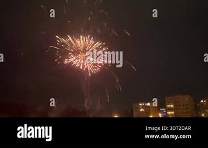 city skyline fireworks burst over residential buildings, colorful pyrotechnics exploding across dark night sky, glowing embers and drifting smoke, rooftop viewers capturing spectacle, festive holiday Stock Video Footage - Alamy