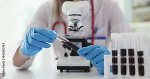 Health care worker analyzes blood sample in a laboratory using a microscope