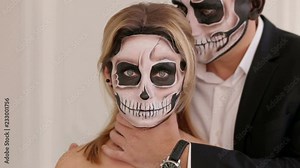 Close-up portrait of a creepy girl with makeup in the form of a skull, a man holding her neck trying to strangle. Women dressed in costume cosplay horror zombies or ghost on Halloween festival. Stock Video