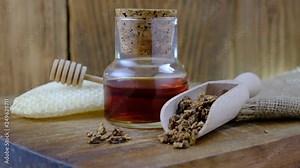 A bottle of propolis tincture and a wooden scoop of propolis granules. Medical preparations bee propolis. Bee glue. Apitherapy. How to treat bee products.