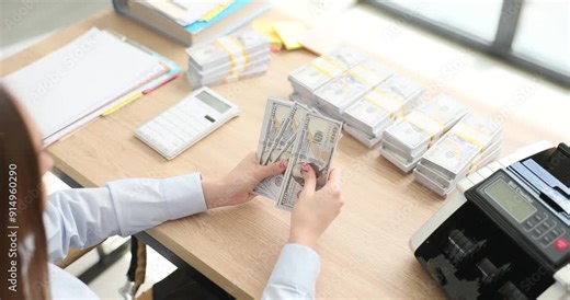 Woman company accountant counts dollar bills in office. Female employee checks got cash sitting at workplace with banknote counter machine