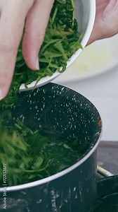Vertical. Adding edible wild fiddlehead ferns or Diplazium esculentum to a pot of boiling for making pako salad, a local Filipino delicacy showing the authentic daily home life and culinary heritage