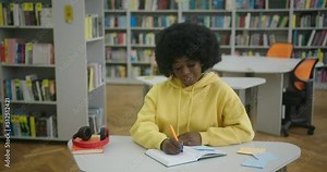 Young black woman makes notes in notepad turning head aside