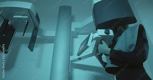 A female patient having 3D scanning of her jaw, she is standing inside of CBCT which is rotating around of her head and her mouth is open, her hands are in the special holder.