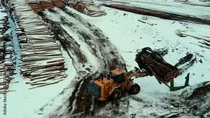 Wheel loader in action at the sawmill as it expertly measures logs with its grapple bucket and specialized sizing instrument