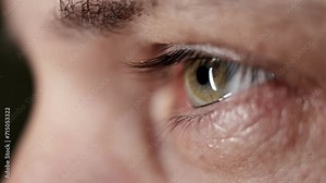 Extreme close-up of a man's eye opening. The man opens his eye and looks. Gray-green eye color.