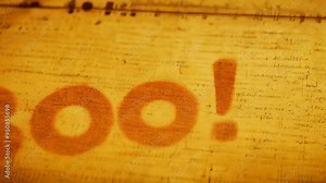 The word "Boo!" appears in Monospaced style, written in rusty orange color on an old typewriter paper background with typewriter ink marks, illuminated by dull yellow light
