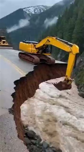 Flood-Damaged Road Nearly Claims Excavator as Embankment Gives Way Buncombe County, North Carolina – A tense moment unfolded during flood recovery efforts when an excavator nearly tipped into a swollen river after the road shoulder beneath it collapsed. Video shows the machine operating on a steep, rain-saturated slope beside fast-moving floodwaters. As the operator works near the edge, the ground suddenly breaks apart, causing the excavator to slide forward toward the channel. The machine hangs