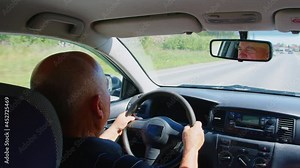 Pensioner is driving car in forest, wooded area. Aged man sits inside auto, holds steering wheel. Save automobile handling. Travel, journey, business trip