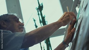 Male architect with glasses at work. Architect working at the window. Architect sitting in front of the easel. Easel for the architect. Draftsman work. Ruler and a pencil in the hand of the architect