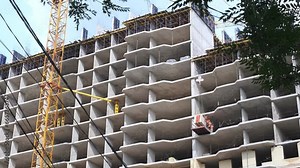 Unfinished building on a construction site. Industrial crane near the building. Concrete building under construction. Construction site background