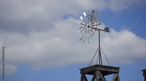 Classic retro windmill, bladed rotor blue sky. Vintage water pump wind turbine, power generator on livestock ranch or agricultural farm. Rural symbol of wild west, rustic suburb. Stock Video