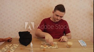The game of the Soviet lotto, unverified barrels and numbers, a guy in a red T-shirt plays a lotto, at the table where there are coffee, medical masks and a hand sanitizer