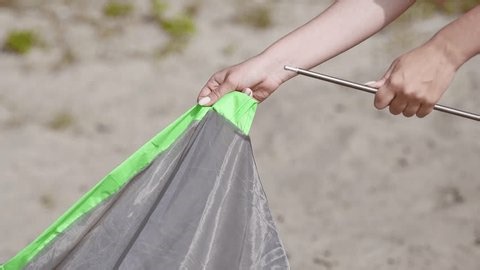 clip-4004355803-hands-threading-flexible-black-tent-pole-through