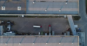 AERIAL. Camera zooming Top Shot of Industrial Warehouse Loading Dock where Many Truck with Semi Trailers Load Merchandise.