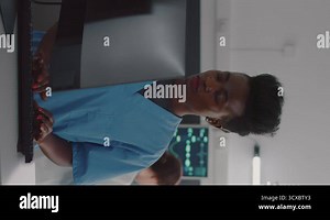 Vertical video: Black nurse typing disease symptom while specialist practitioner doctors checking sick woman Stock Video Footage - Alamy