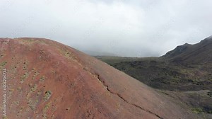 Aerial view red volcano crater on Haleakala peak on remote tropical Hawaii island Maui. Hiking trail in national park USA. Outdoor adventure and nature travel background. Old volcano covered by clouds