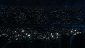 Crowd waving cellphones and flashlights at stadium during rock...