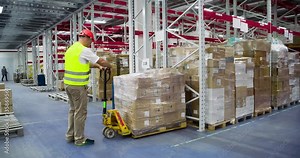 Warehouse worker transports boxes on trolley loader 4k video. Delivery man unloading hand truck platform and pulling cargo, walking at storage
