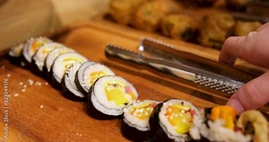 Sushi roll is taken with chopsticks for sushi close-up. Japanese cuisine sushi in a restaurant. Sushi roll with salmon and vegetables. Japan restaurant menu. Side view.