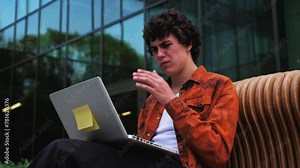 Man shocked by reading news on laptop screen while sitting outdoorsner moder business office. Shocked frightened man read bad news on internet, crisis and collapse in business concept.