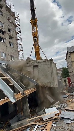 A unfinished concrete building structural failure after a crane arm strikes the upper framework.