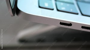 Close up rotation movement of USB type c port for connection in laptop with blur Thai keyboard