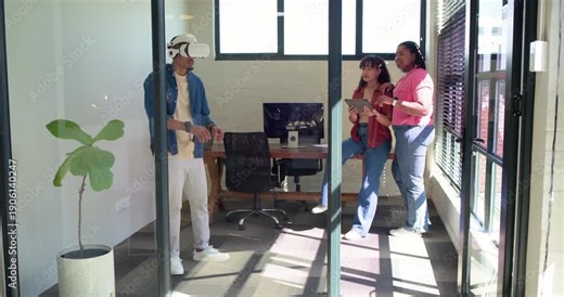 Coworkers watching man testing VR headset after activation in meeting room, checking tablet
