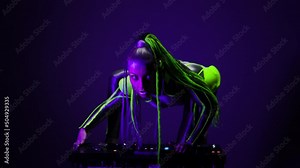 Portrait of slim woman in futuristic costume with fluorescent makeup bending performing gymnastics moves on DJ set looking at camera. Flexible performer posing in darkness in violet lights