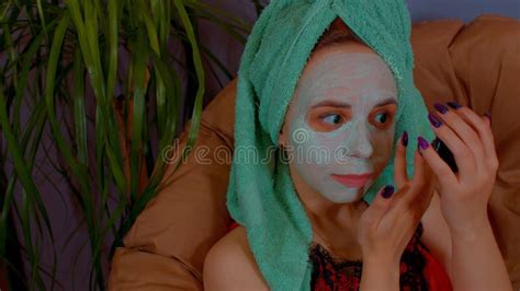 Young Woman With Towel On Head Applies Mask On Face Sitting In Armchair Lady Caring Of Her