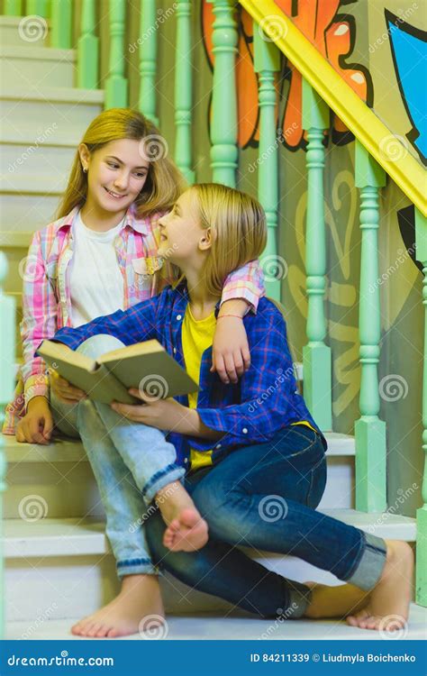 Nette Mädchen Mit Dem Halten Des Buches Und Dem Sitzen Auf Der Treppe Der Leiter Innen Stockbild