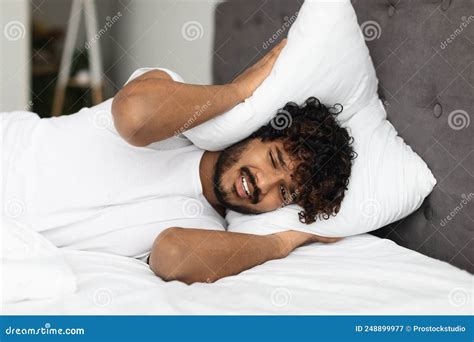 Angry Eastern Man Laying In Bed Covering Head With Pillow Stock Image Image Of Financial