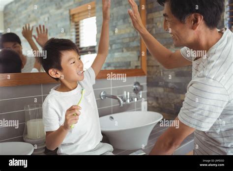 Father And Son Giving High Five To Each Other In Bathroom At Home Stock