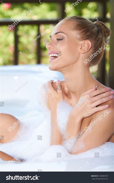 Vivacious Blonde Woman Laughing In Enjoyment As She Soaks In The Soapy Bubbles Of Her Bubble