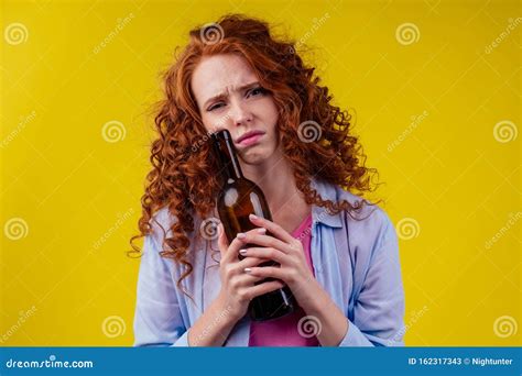 Curly Redhead Ginger Woman Drinking Beer And Feeling Bad Mood In Csudio Yellow Background Stock