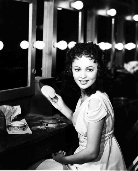 A Black And White Photo Of A Woman Sitting At A Table With An Apple In