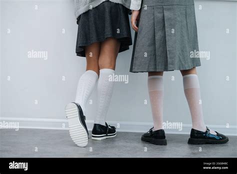 Legs Of Two Schoolgirls Stadning Next To A Wall Close To One Another Both Wearing Skirts And
