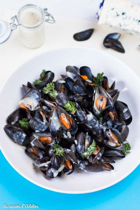 A White Bowl Filled With Mussels And Broccoli On Top Of A Table