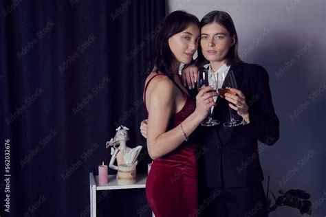 Cropped Close Up Shot Of A Two Lesbian Girls With Glasses Of White Wine Are Cuddling In A Room