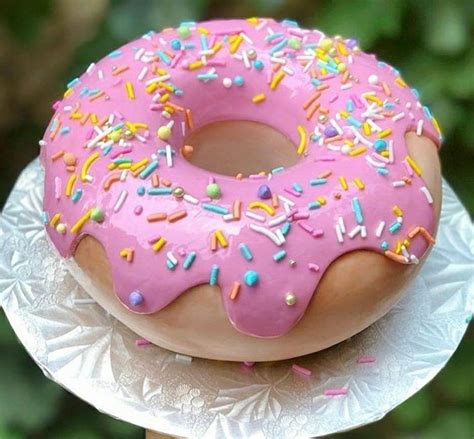 A Donut With Pink Frosting And Sprinkles On A White Plate