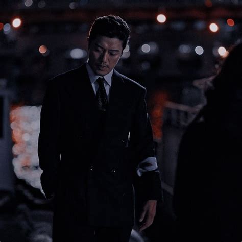 A Man In A Suit And Tie Standing Next To Other People