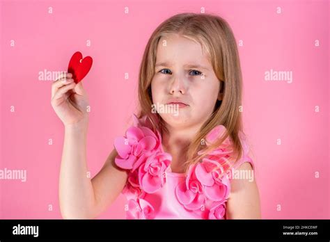 Upset Cute Little Blue Eyed Girl With Long Fair Hair In Chic Pink Dress Pose Holding Red Paper